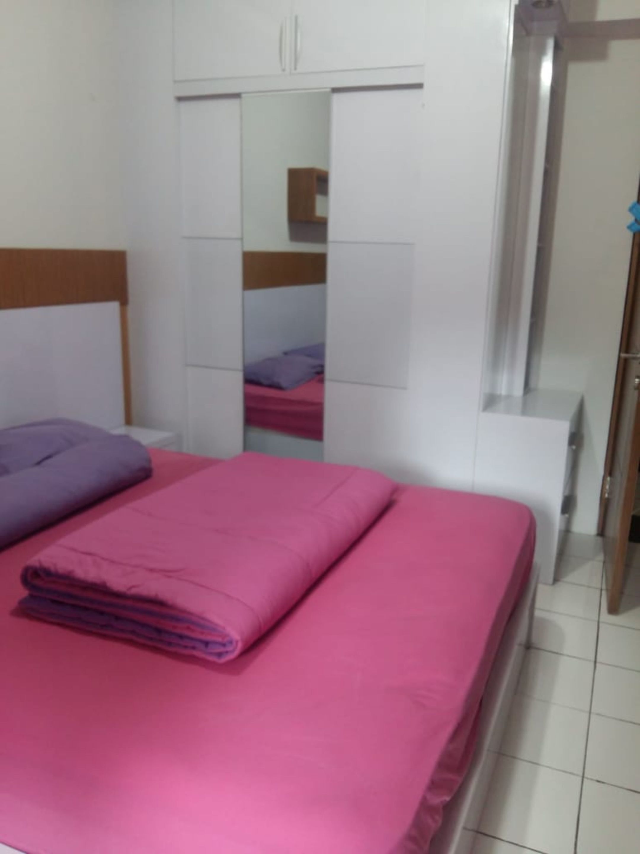 Quarto com cama, guarda-roupa e espelho.