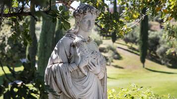 Estátua de uma mulher segurando um cordeiro em um jardim.