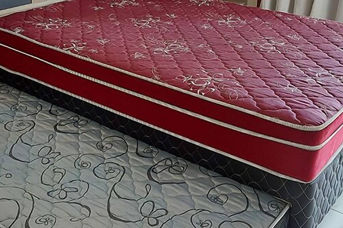 Dois colchões empilhados em um quarto com piso de azulejos.