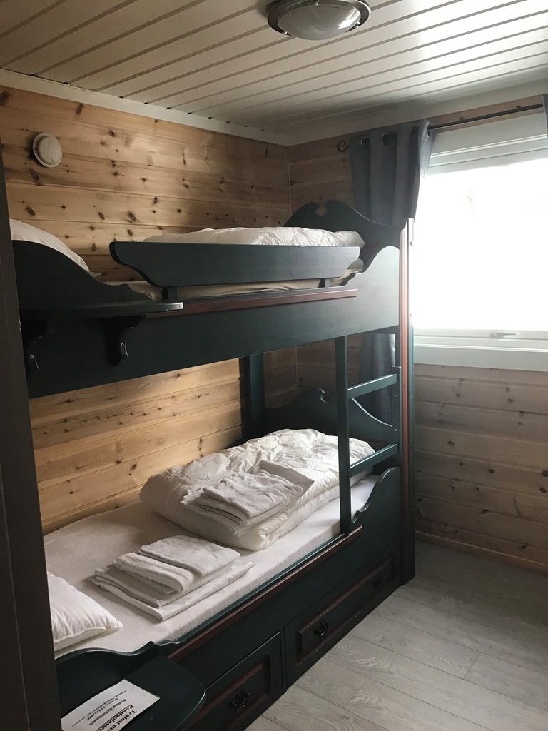 Quarto com beliches, paredes de madeira e uma janela.