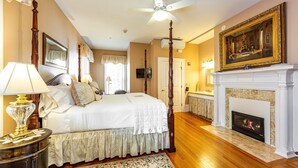 Quarto com cama de dossel, lareira e ventilador de teto.