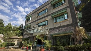 Um edifício moderno de dois andares com entrada coberta, área de estar externa e plantas em vasos.