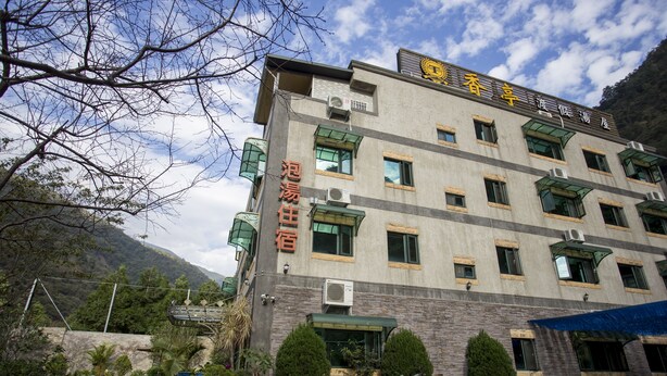 Um hotel de vários andares com fachada de pedra, várias janelas e uma placa indicando ser um hotel.