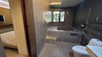 Uma casa de banho moderna com banheira, sanita e chuveiro.