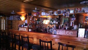 Uma área de bar com balcão e banquetas de madeira.