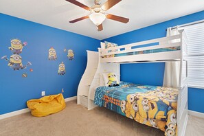 Quarto com beliche, um pufe e adesivos de parede com os personagens Minions.