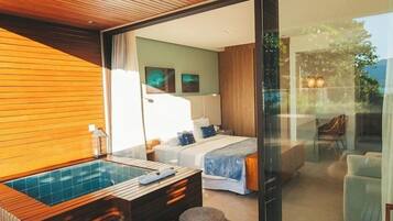 Quarto moderno com porta de vidro para uma varanda, área de banho em madeira e cama com manta azul.