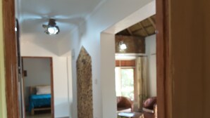 Um corredor que dá para um quarto com cama, parede de madeira e janela.
