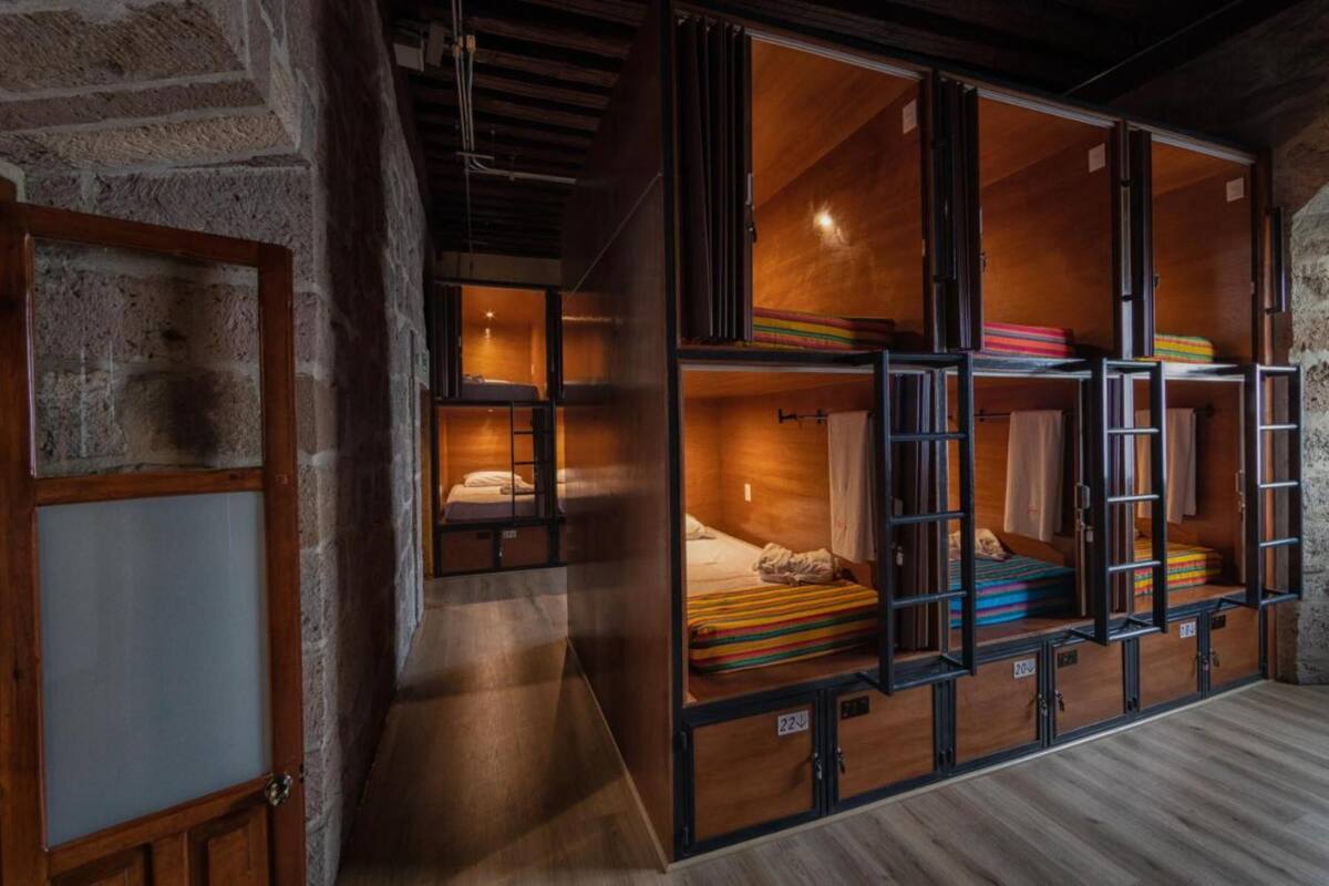 Quarto com beliches, paredes de madeira e uma parede de pedra.