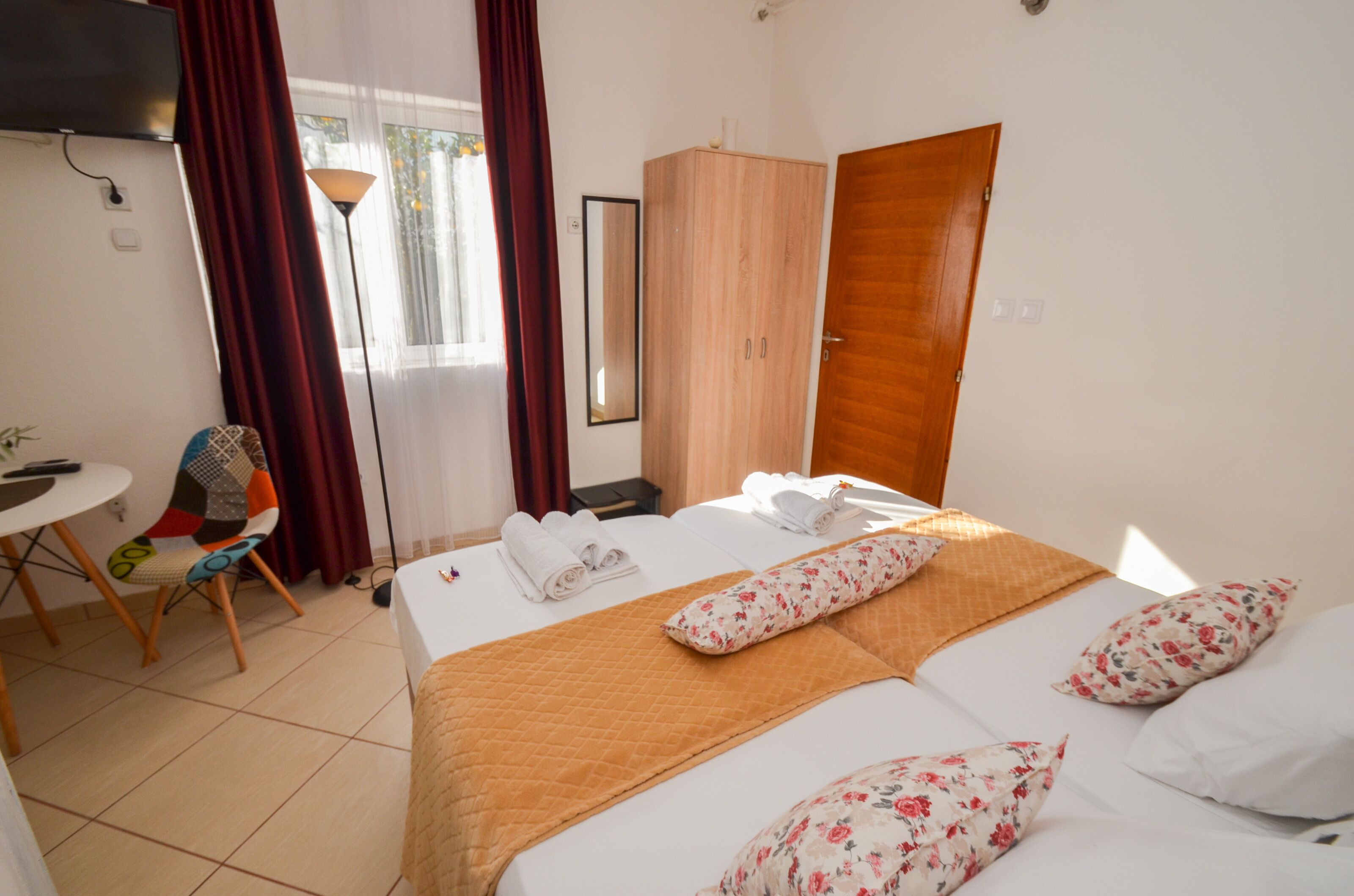 Quarto de hotel com cama, escrivaninha, cadeira, guarda-roupa e espelho.