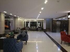 Um lobby moderno com área de estar, balcão de recepção e elevador.