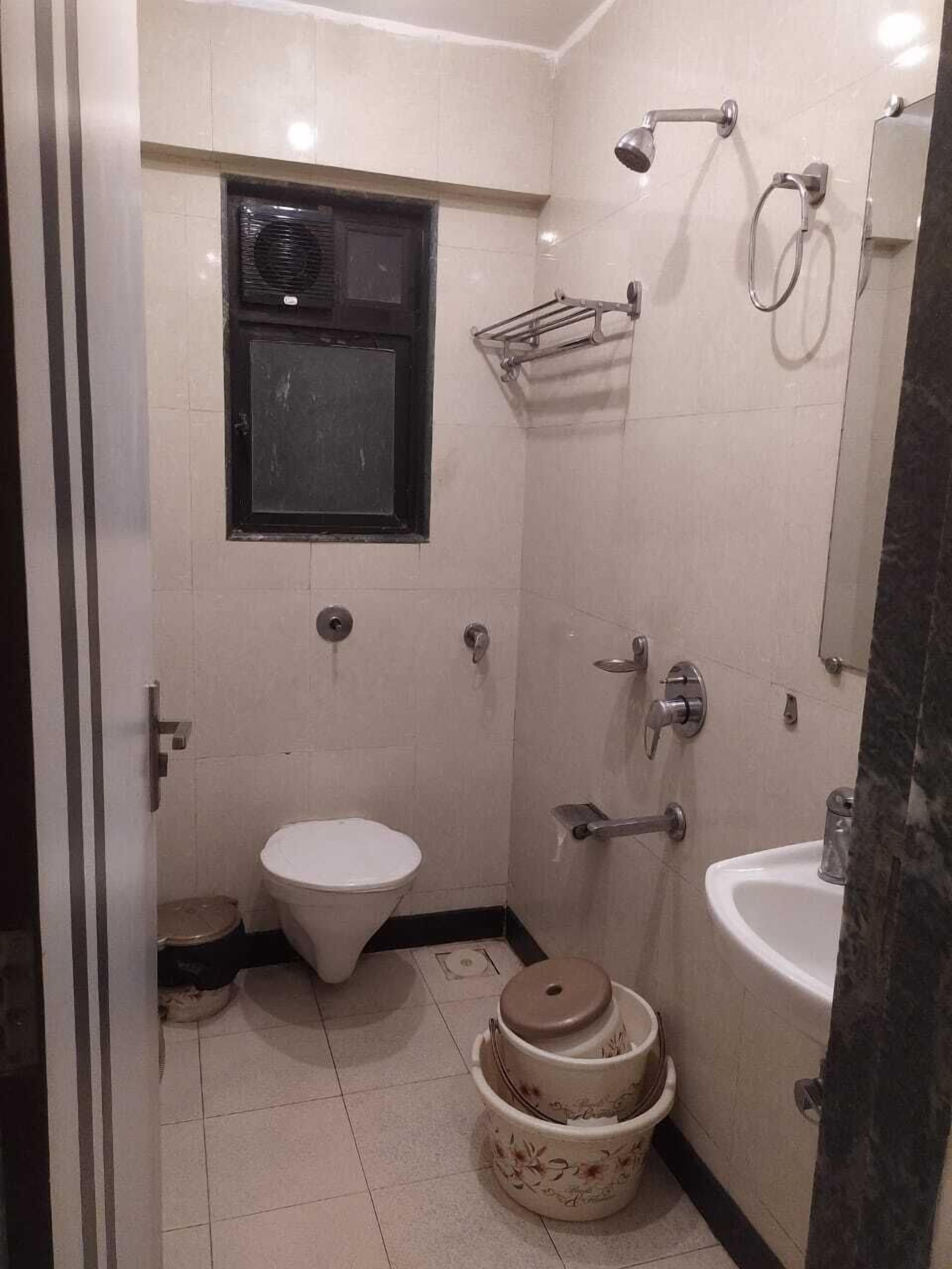 Casa de banho compacta com sanita, lavatório, chuveiro e janela.
