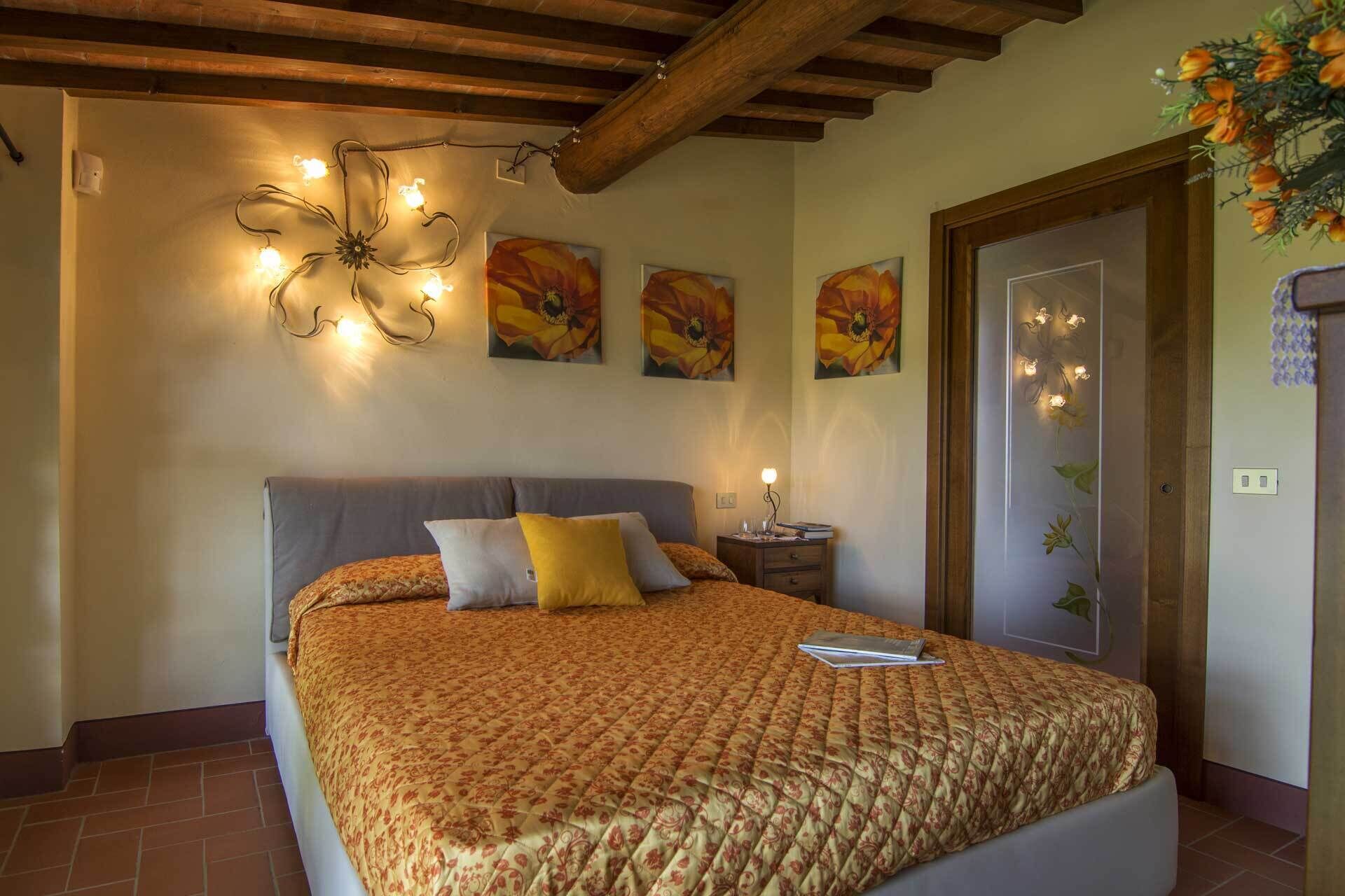Quarto com cama, mesa de cabeceira e luzes de flores na parede.