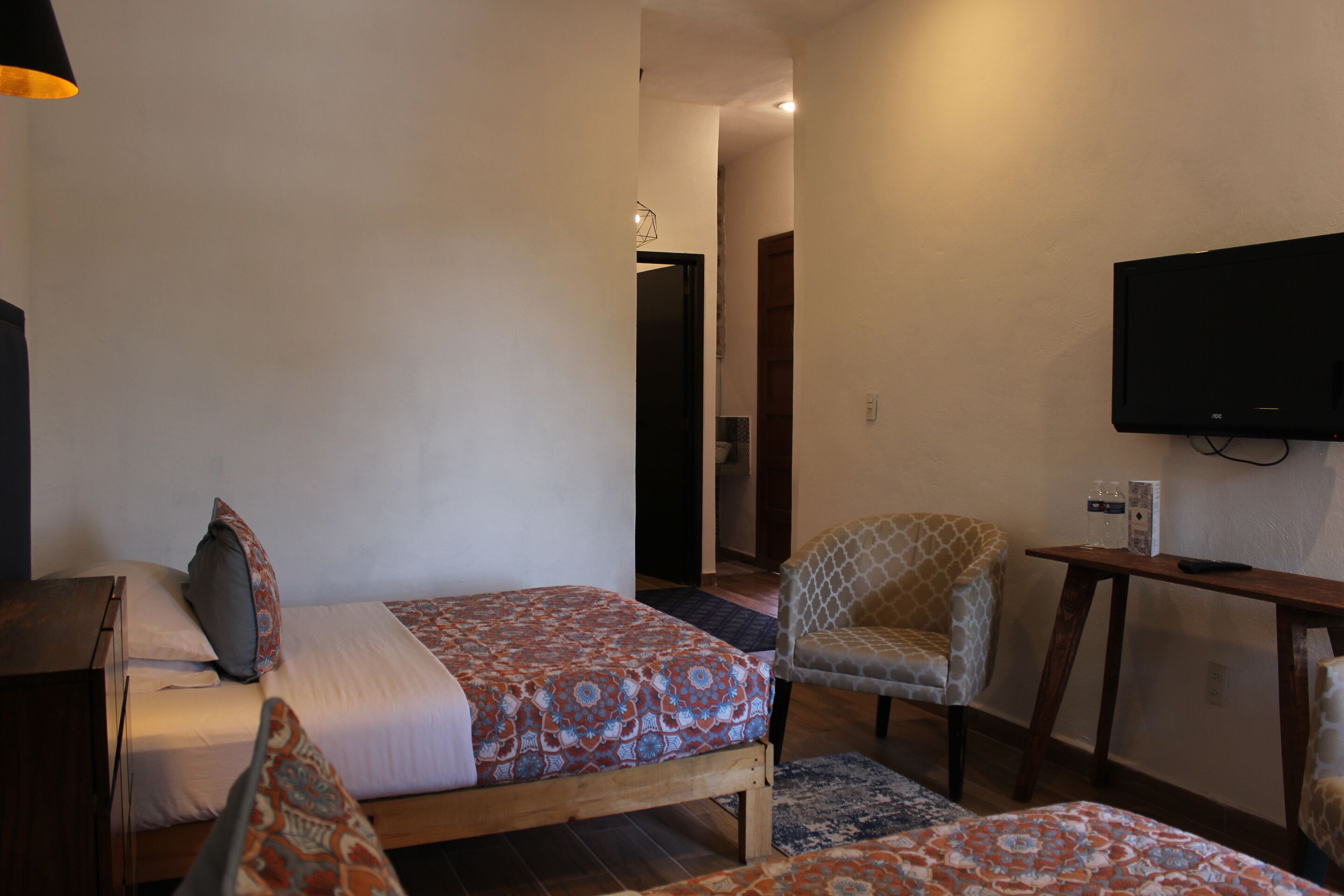 Quarto de hotel com duas camas, televisão, uma cadeira e uma escrivaninha.