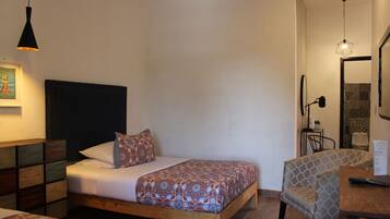 Um quarto com cama de madeira, mesa de cabeceira, cadeira e escrivaninha.
