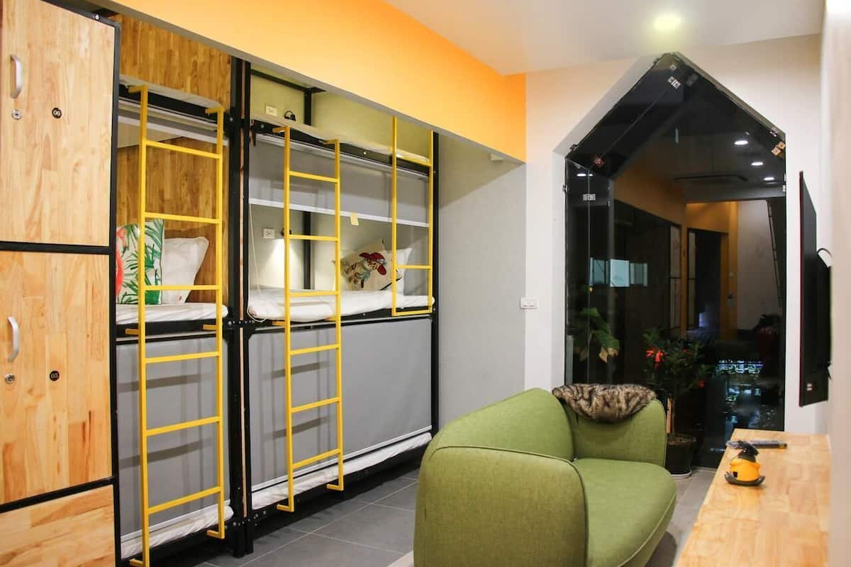 Um espaço compacto com beliches, um sofá verde e uma mesa pequena.