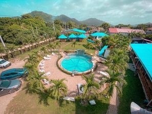 Resort com piscina central, espreguiçadeiras e palmeiras.