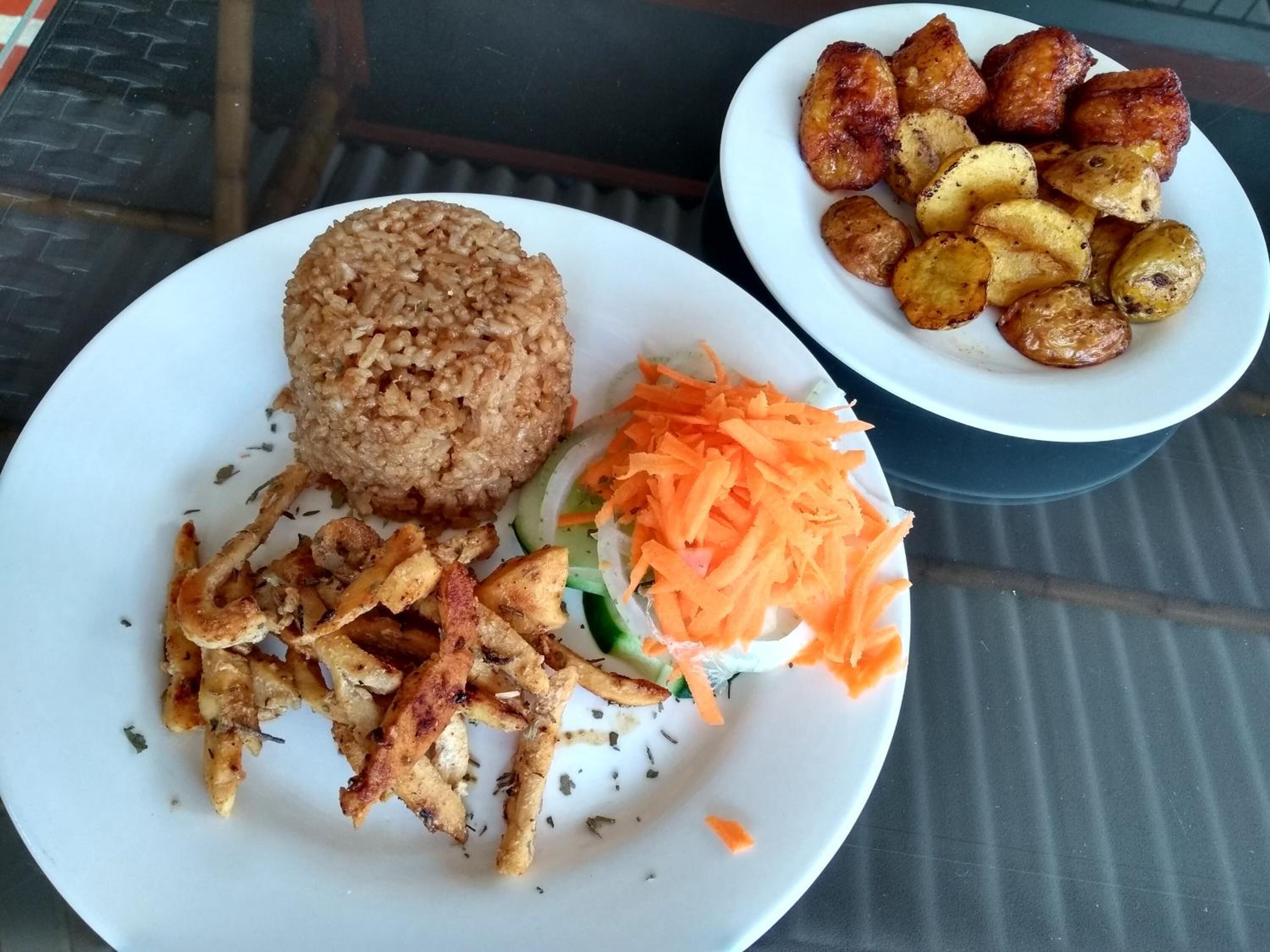 Um prato com arroz frito, frango frito e uma guarnição de cenoura e pepino ralados.