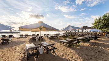 Praia de areia branca, espreguiçadeiras, guarda-sóis de praia