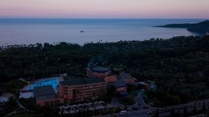 Um resort com piscina, um edifício grande com vários andares e vista para o mar.