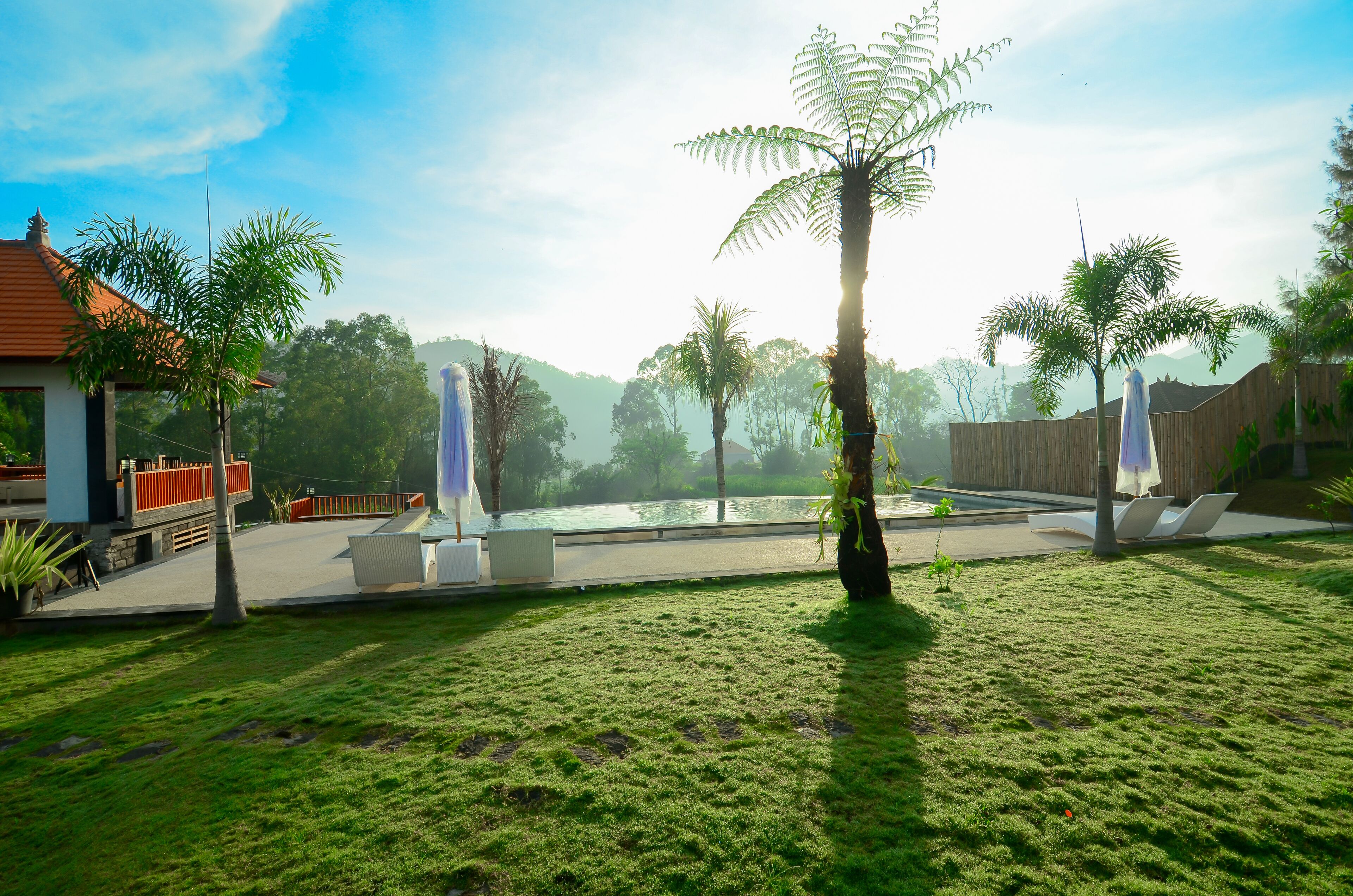 Um jardim bem cuidado com piscina, áreas de estar e cerca de madeira.