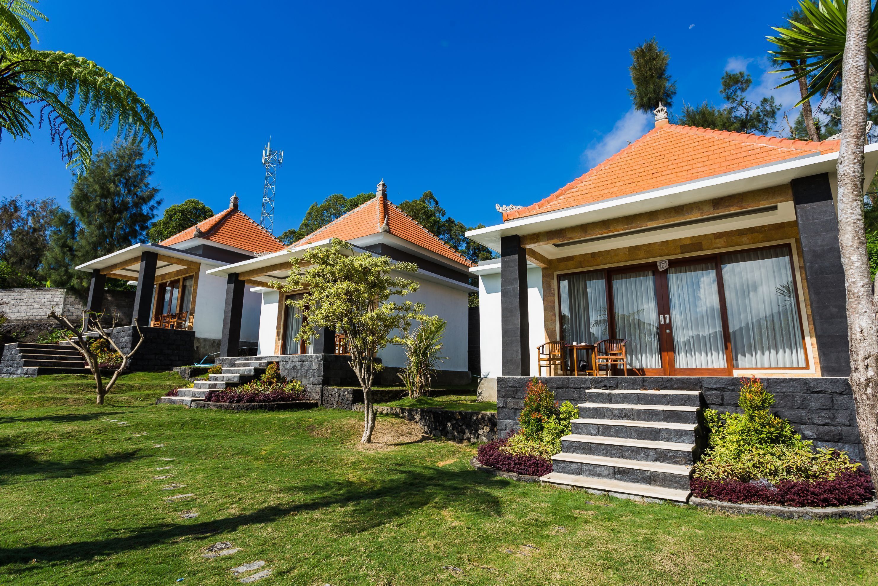 Uma casa moderna com telhado ladrilhado, varanda coberta e um jardim bem cuidado.