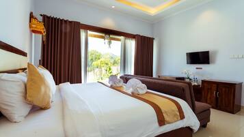 Quarto de hotel com cama grande, sofá, TV e vista para o exterior.