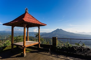 Um gazebo com telhado vermelho com vista para uma paisagem montanhosa.