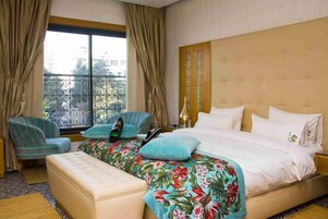 Quarto de hotel com cama, uma cadeira e um banco.