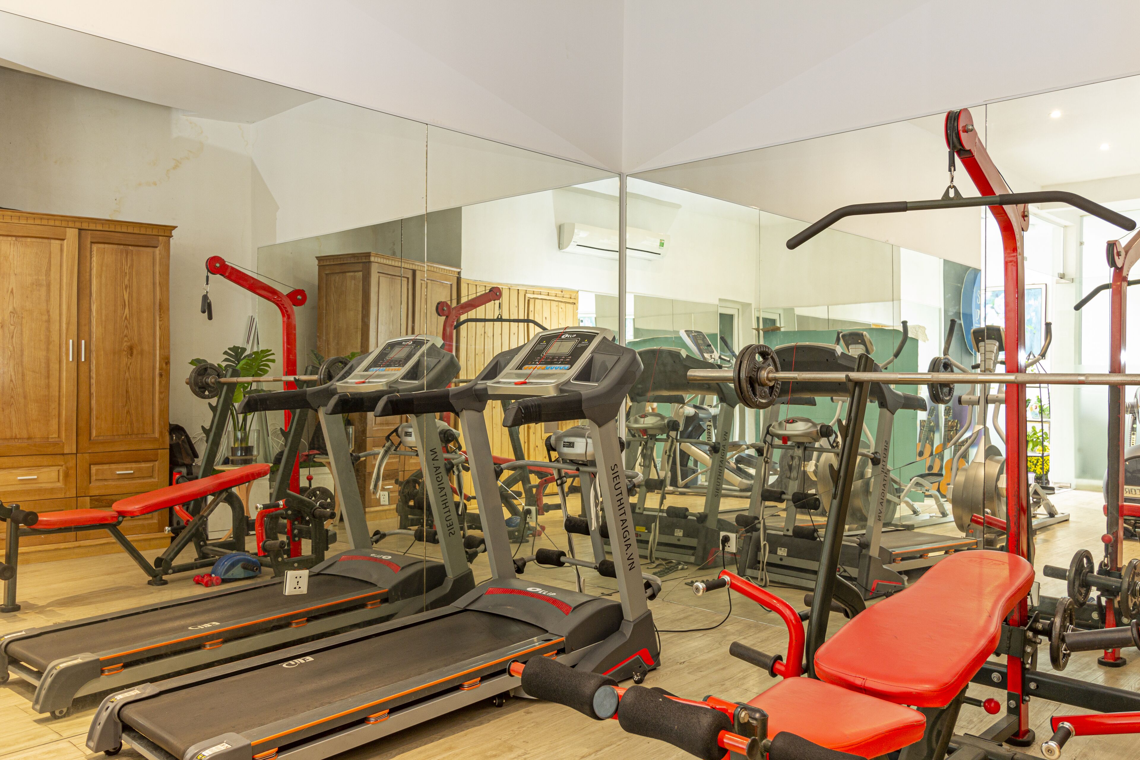 Academia com esteiras, aparelhos de musculação e um banco.