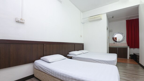 Quarto de hotel com duas camas, cabeceira de madeira, espelho e cortina vermelha.