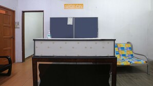 Quarto com cama, uma cadeira, uma escrivaninha e um letreiro com a inscrição SPOT ON.