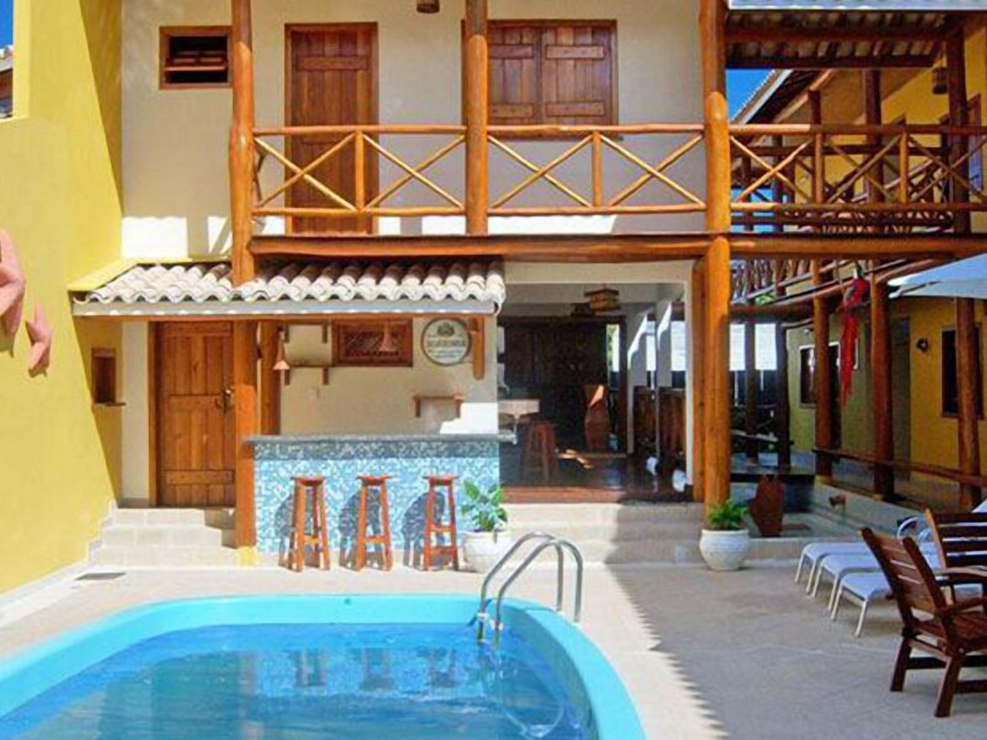 Um edifício de dois andares com piscina, área de estar ao ar livre e varanda coberta.