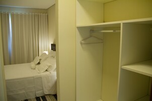 Quarto de hotel com uma cama, um cabide e um guarda-roupa.