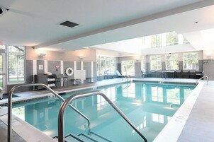 Piscina interior com água cristalina, uma cadeira de salva-vidas e aviso de proibição de mergulho.