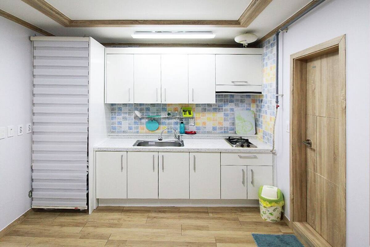 Uma cozinha compacta com armários brancos, pia, fogão e painel de azulejos.