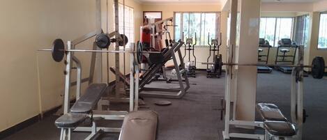Uma academia com diversos equipamentos de exercício, incluindo bancos e aparelhos de musculação.