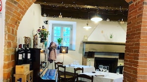 Uma área de refeições aconchegante com um arco de tijolos, um piano e uma mesa posta para dois, com velas.