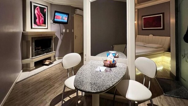 Quarto de hotel compacto com área de refeições, televisão, lareira e uma cama.
