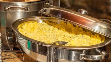Disposição de buffet com um grande recipiente metálico contendo ovos mexidos.