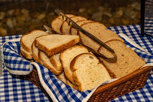 Uma cesta com fatias de pão sobre um tecido xadrez.