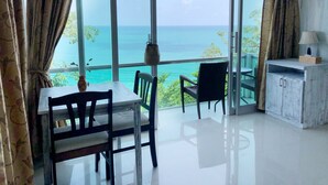 Quarto com vista para o oceano, uma mesa com cadeiras e um armário.