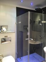 Uma casa de banho moderna com chuveiro em cabine de vidro, lavatório e sanita.