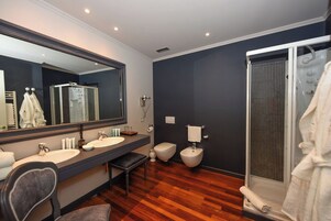 Uma casa de banho moderna com um espelho grande, duas lavatórios, um bidé e um chuveiro italiano.