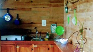 Uma cozinha rústica com armários de madeira, uma pia e utensílios pendurados.