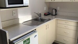 Uma cozinha compacta com micro-ondas, pia e armários.
