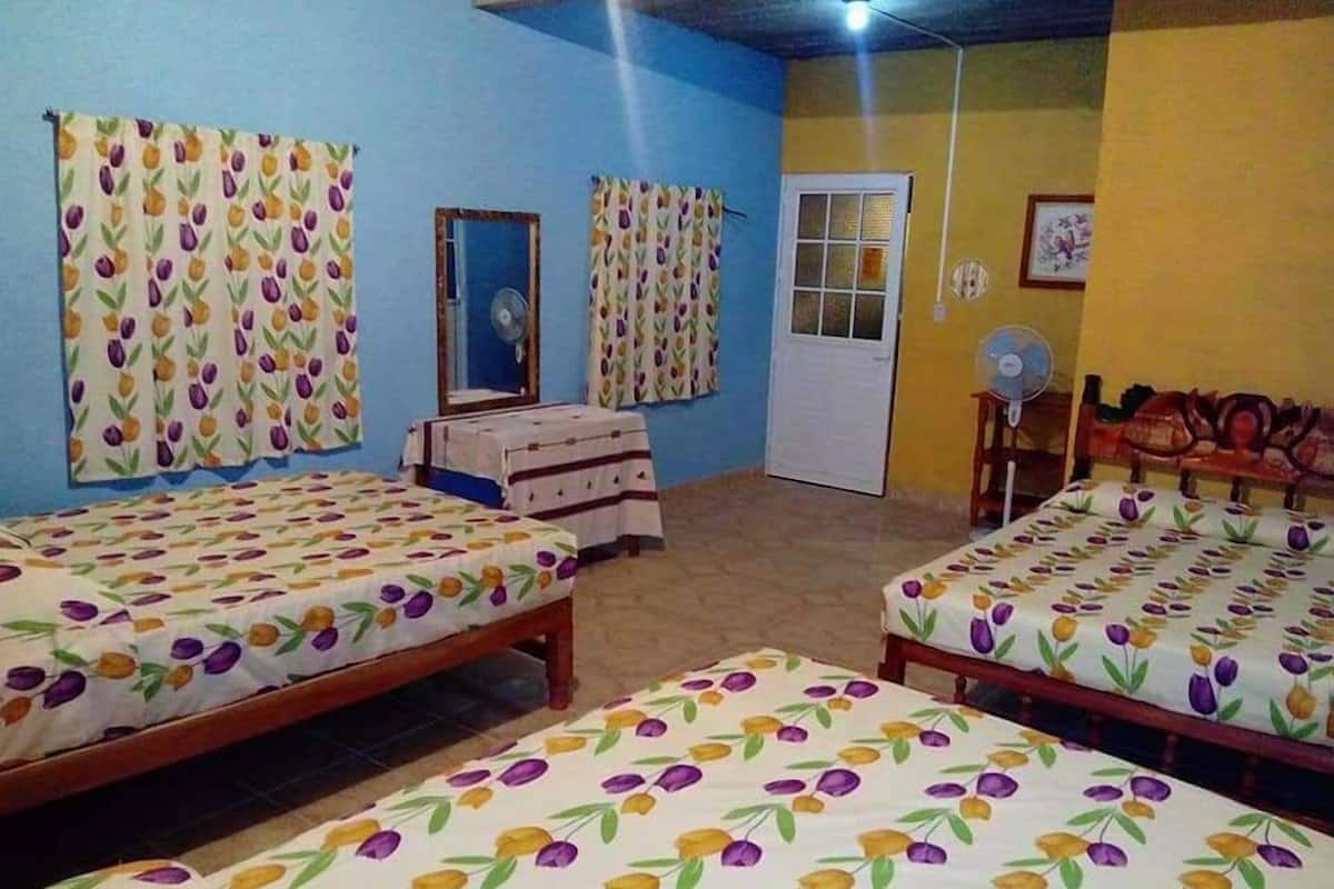 Quarto com duas camas, um espelho, um ventilador e uma porta.