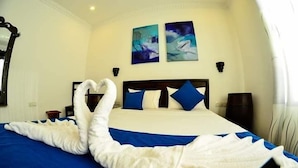 Quarto de hotel com uma cama, duas pinturas na parede e um roupão branco sobre a cama.