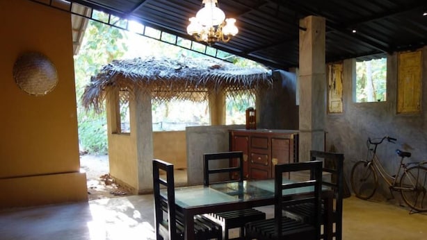 Uma sala de jantar com teto de palha, um candelabro e uma bicicleta.