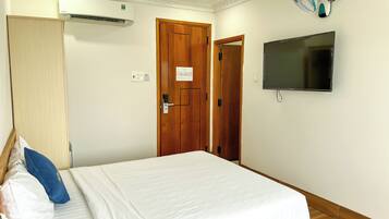 Quarto de hotel com cama, televisão, ar condicionado e porta de madeira.